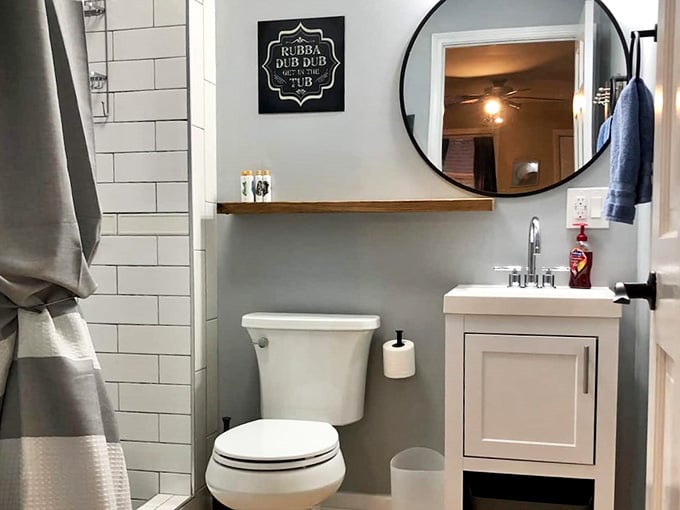 White subway tile, a round mirror, and a "Rubba Dub Dub" sign, clean, clever, and completely charming.