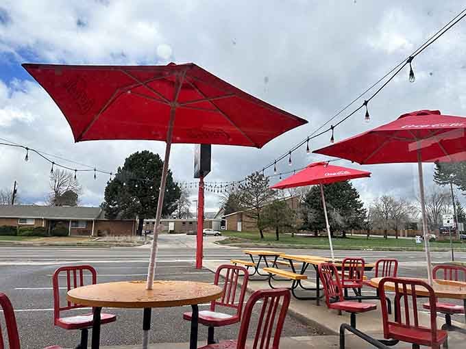 Red Coca-Cola umbrellas, string lights, and metal chairs scattered under an open sky. Outdoor dining here feels like a neighborhood block party that never ended