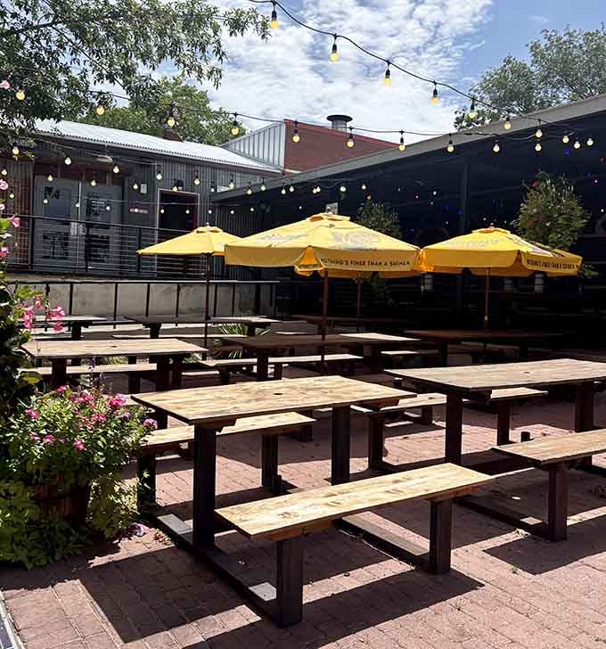 String lights, yellow umbrellas, blooming flowers, and wooden picnic tables under an open Texas sky, the outdoor patio is genuinely delightful.