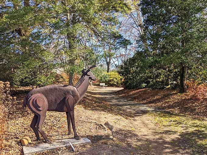 A metal deer sculpture stands guard on a sun-dappled path, welcoming wanderers with quiet dignity.