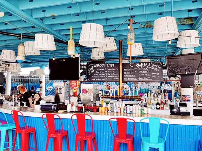 A bright blue bar, pendant lamps overhead, and a full cocktail menu on the chalkboard. Brooklyn Crab's bar area looks like summer decided to stay permanently.