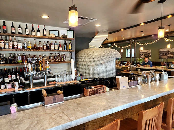 The bar showcases that impressive wood-fired oven, turning pizza-making into dinner theater you can actually eat.