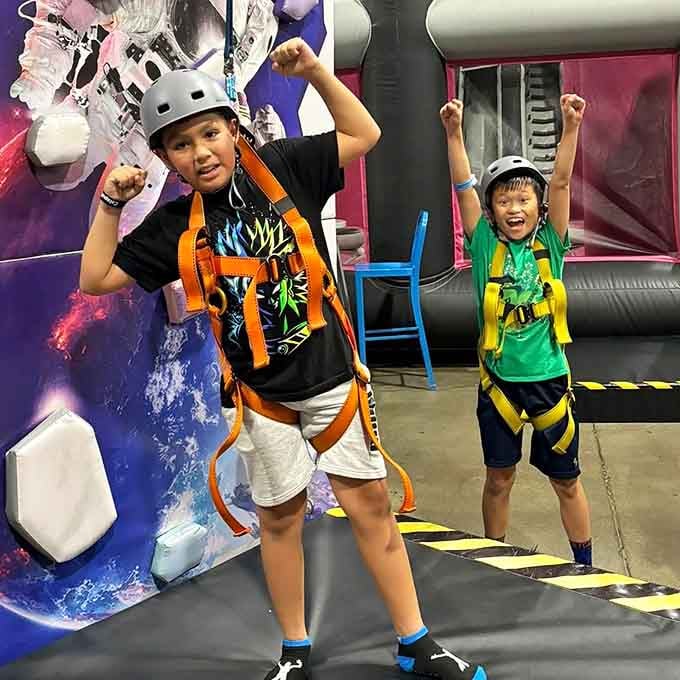 Arms up, helmets on, smiles mandatory. These two just conquered the climbing wall and they want everyone to know it.