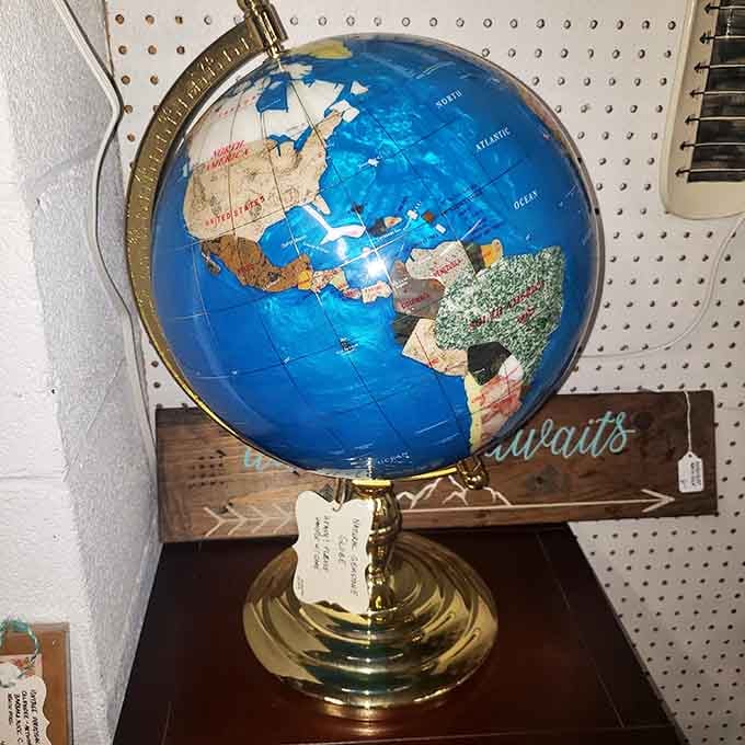 A natural sapstone globe on a brass stand, quietly reminding you that the whole world fits in one booth.