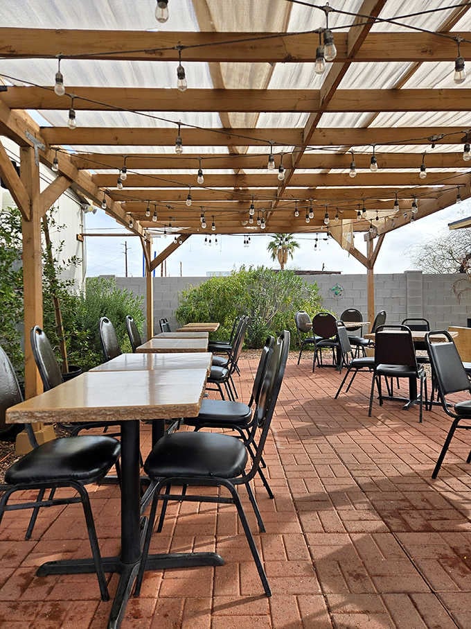 String lights overhead, brick underfoot, and a palm tree peeking over the wall — this patio was built for long evenings.