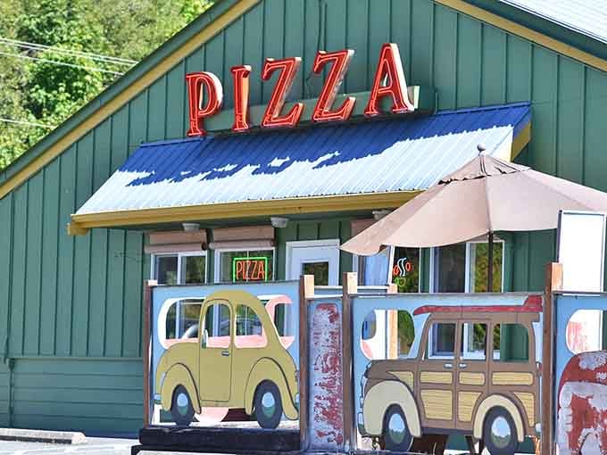 That red pizza sign glowing against a green building is the universal language everyone speaks fluently.
