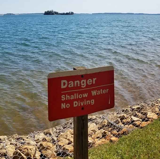 Safety signs reminding you to wade, not dive, because even paradise has sensible rules.