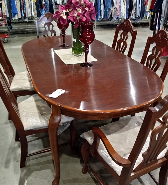 A polished cherry wood dining set dressed with flowers and glassware, elegant enough for a dinner party, priced for a Tuesday afternoon.