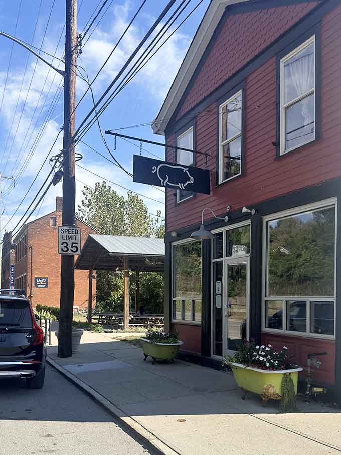 Sunshine, a swinging pig sign, bathtub planters bursting with flowers, and the faint smell of smoke drifting out to greet you.