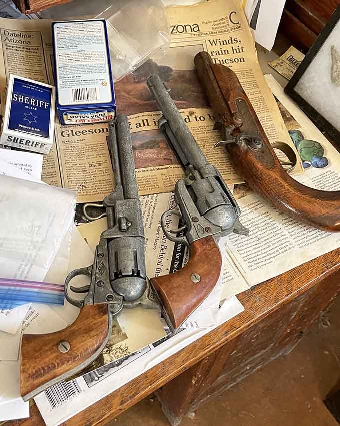 Antique firearms rest on old newspapers, creating a display that's equal parts museum exhibit and time machine.