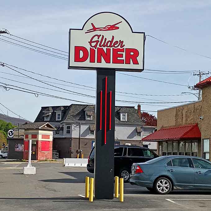 Bold red lettering, a soaring glider logo, and a parking lot full of cars, this roadside sign delivers on every single promise.