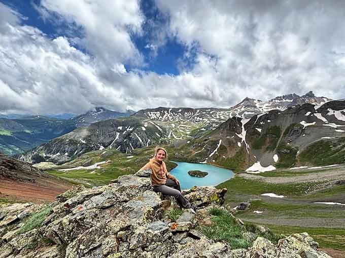 Perched high above the basin, she's got the whole magnificent sweep of Ice Lake and the San Juans laid out behind her.