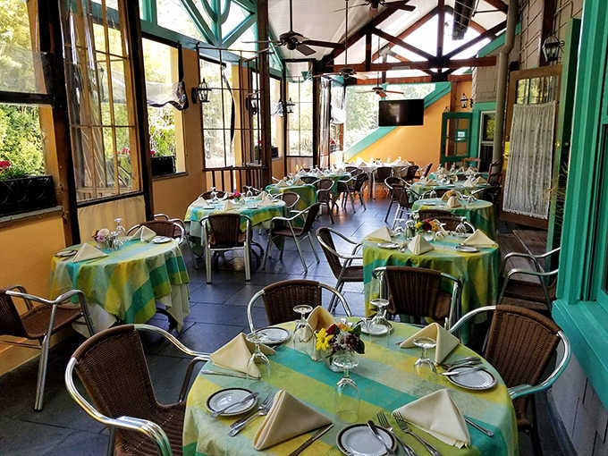 The sunny enclosed porch with cheerful green and yellow tablecloths is where a lazy French afternoon comes to life in Maryland.