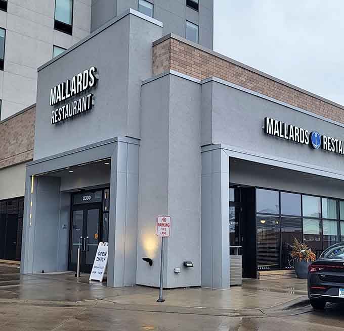 The corner entrance glows warmly against an overcast sky, a quiet signal that something worth stopping for is just through those doors.