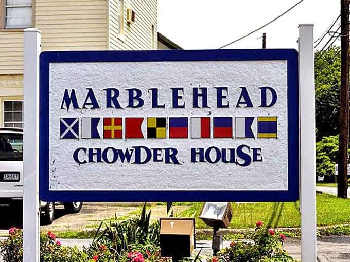 Maritime signal flags and bold lettering, this sign is the first clue that something genuinely special is happening just beyond the parking lot.