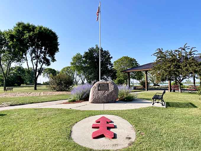 A bold red arrow marker points the way at Red Arrow Park, where a granite memorial, a flagpole, and river views create a moment worth pausing for.