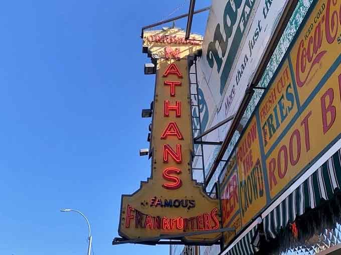 That vintage neon sign spelling out "Famous Frankfurters" against a clear blue sky is the most honest piece of advertising in New York City.