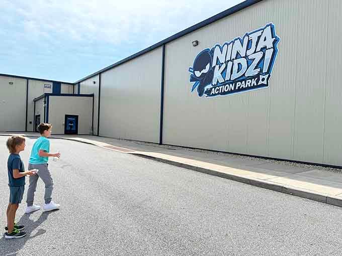 Two kids pointing at the bold Ninja Kidz Action Park sign outside, already plotting their first move before they even walk in.