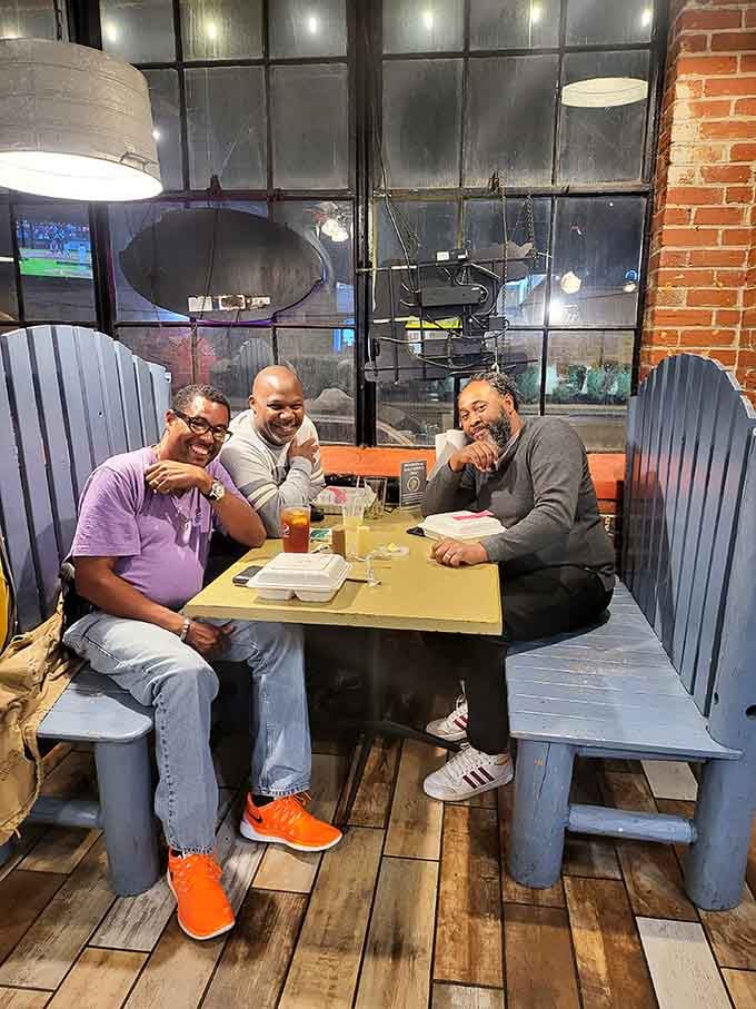 Three guys, big smiles, and takeout containers on the table. Good BBQ has a funny way of bringing people together.