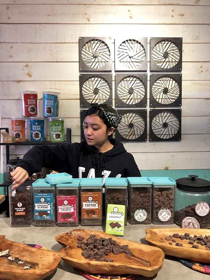 Behind the tasting counter, a Taza staff member arranges chocolate samples with the focus of a true chocolate devotee.