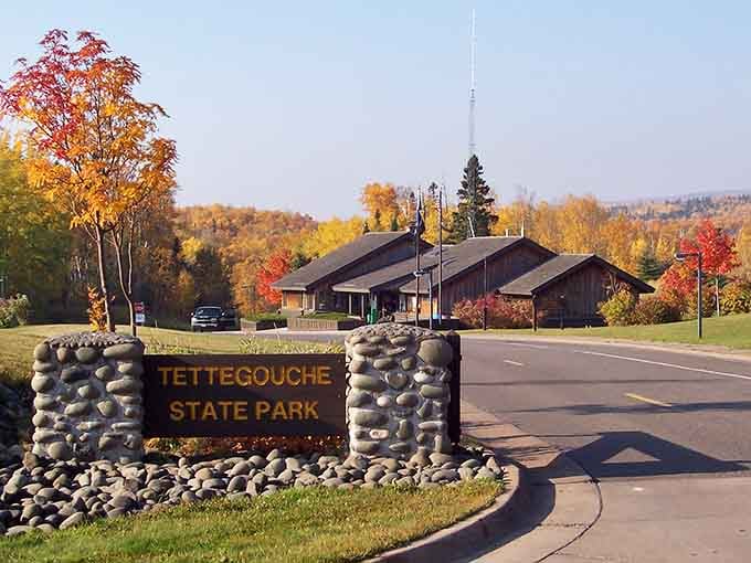 The stone entrance sign stands proudly against a full autumn blaze, announcing that something truly spectacular waits just beyond this point.