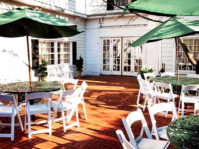 A sun-drenched brick courtyard with green umbrellas and white chairs. Fresh air, good food, and zero complaints.