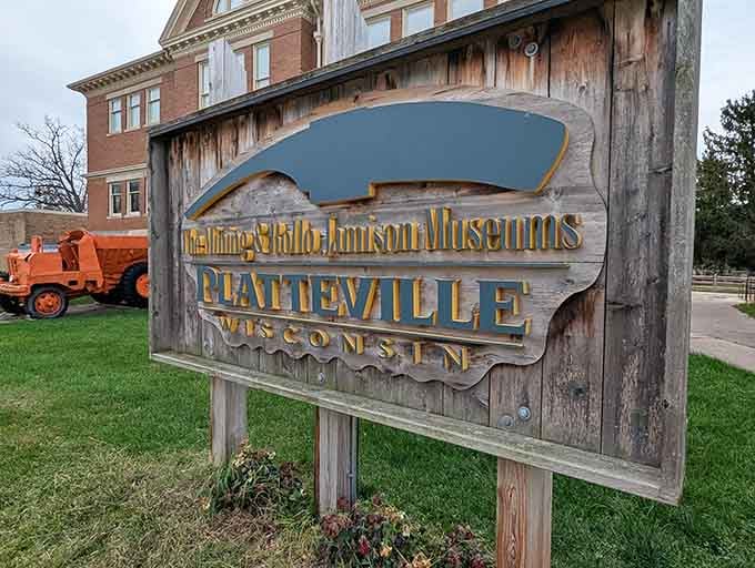 That weathered wooden sign says it all — two museums, one remarkable Wisconsin town, and zero reasons to skip it.