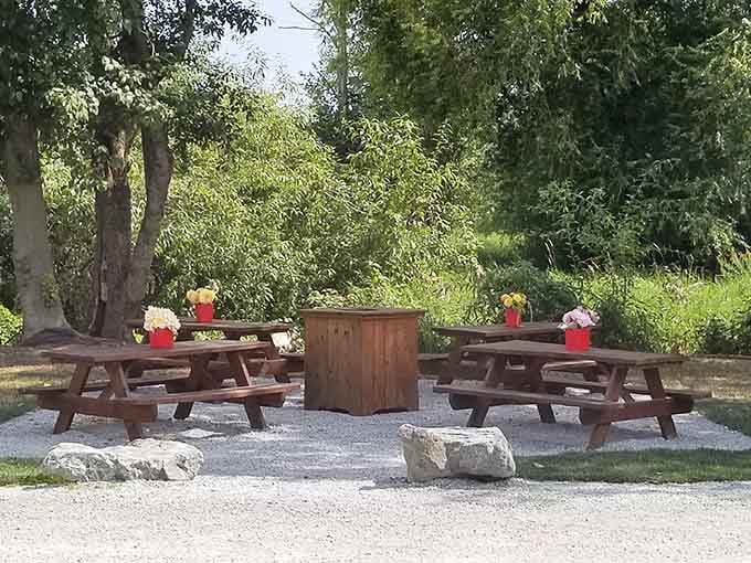 Picnic tables, fresh flowers, and tall trees overhead. Eating outside here feels less like lunch and more like a small celebration.