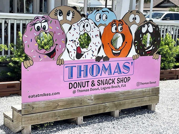 Five cartoon donuts grinning from a pink sign, because if your food spot has a mascot this cheerful, you're in good hands.