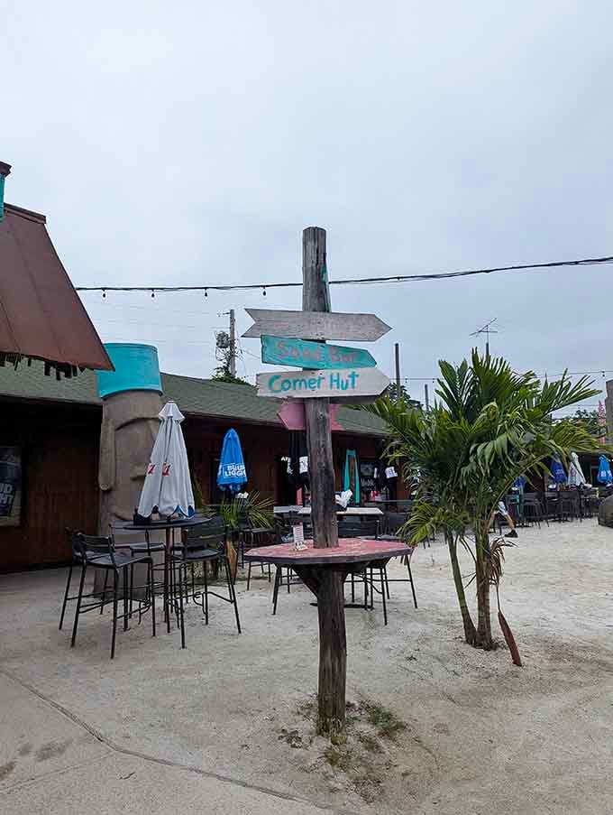 Weathered wooden signposts pointing toward the Sling Bar and Corner Hut, because paradise apparently has its own neighborhood map.