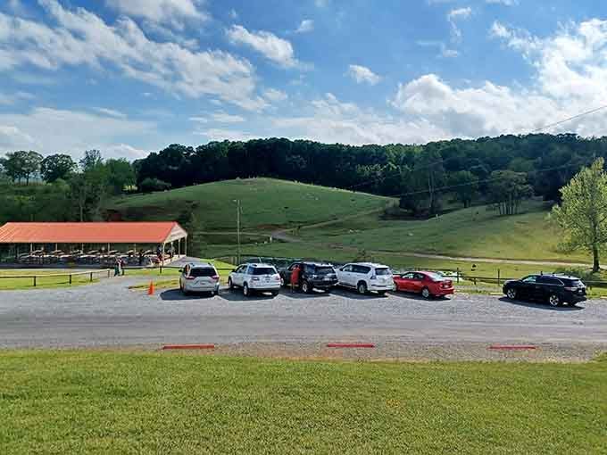 The parking area with rolling hills beyond, your first hint that something extraordinary awaits just past those gates ahead.