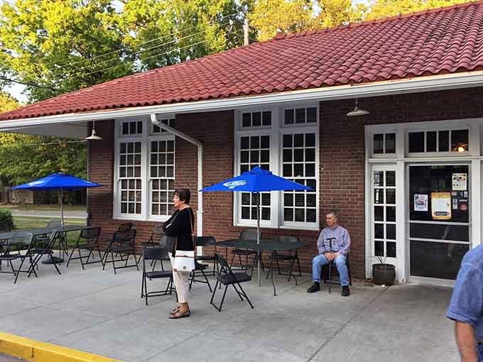 The old train platform patio, where folding chairs and blue umbrellas turn a sunny afternoon into something worth remembering.