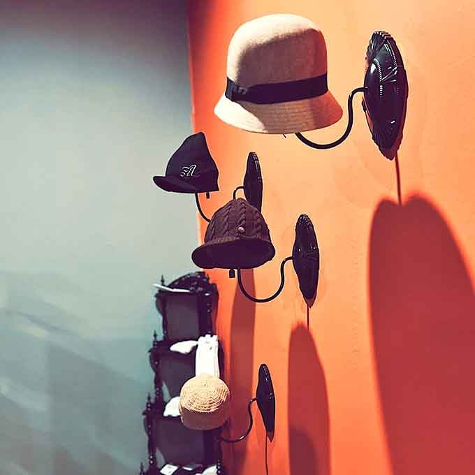 Hats mounted on an orange wall like a gallery exhibit. Stylish, playful, and somehow exactly what your wardrobe has been missing.