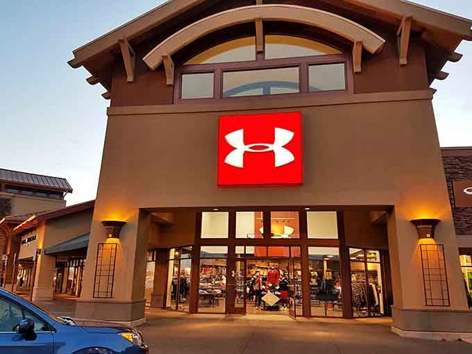 The Under Armour storefront glowing at dusk, looking less like an outlet store and more like a sports cathedral.
