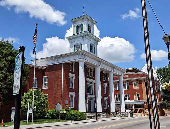 Admire the grand brick architecture and towering white pillars of this historic courthouse building standing proud under a sunny sky.