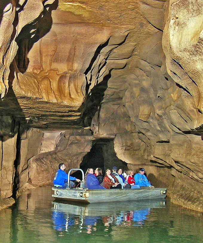 Indiana's underground secret: a glowing cave river carrying wide-eyed passengers into golden, ancient darkness.