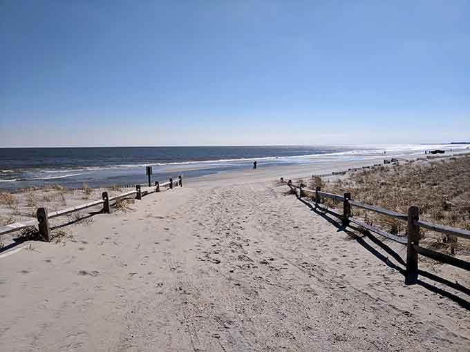 That wooden fence leading to pristine sand is your gateway to peace and quiet by the ocean.