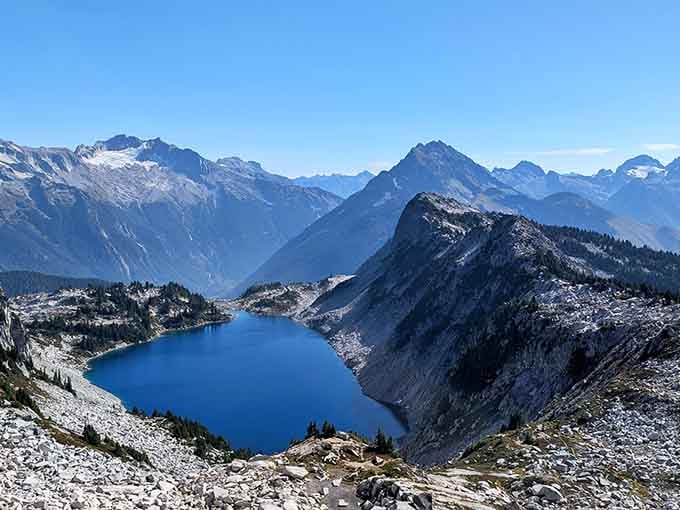 That deep blue lake nestled between snow-capped peaks is nature showing off, and honestly, good for it.