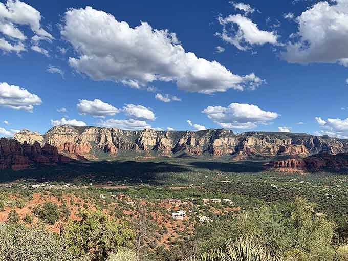 Fluffy clouds drift lazily above a canyon panorama so vast it practically demands a standing ovation.