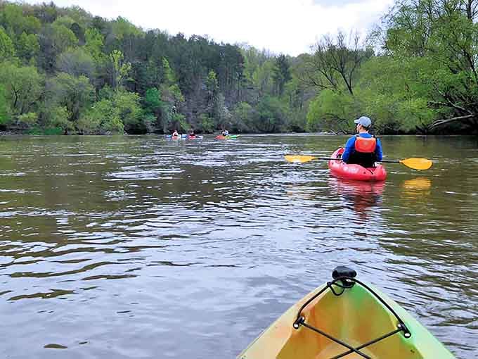 The French Broad stretches ahead like glass, inviting kayakers to glide through mountain-framed tranquility and endless green.