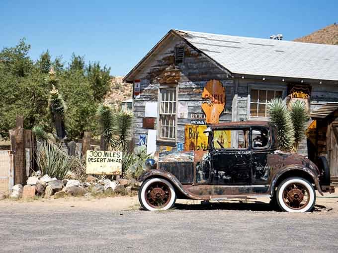 That "300 Miles Desert Ahead" sign isn't a warning, it's an invitation, and this charred old Model T already knows it.