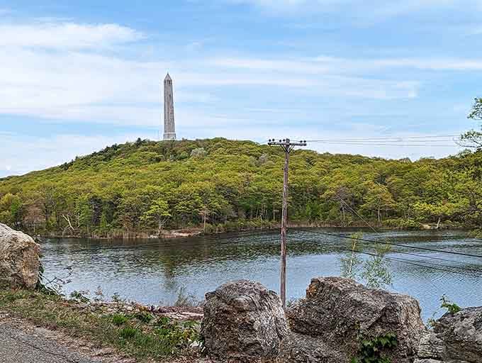 Spring's fresh green canopy frames the monument perfectly, with lakeside boulders adding a rugged, front-row seat to the view.