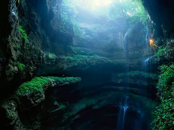 Moss-draped walls, a hidden waterfall, and glassy dark water — Neversink Cave feels like Middle-earth moved to Alabama.