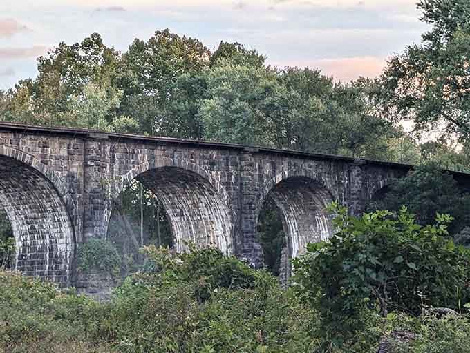 This ancient stone railroad viaduct rising through the trees looks like it wandered straight out of a European countryside painting.