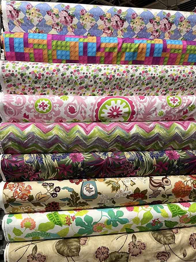 Bolts of color stacked like a textile rainbow, every pattern more tempting than the last one you spotted.