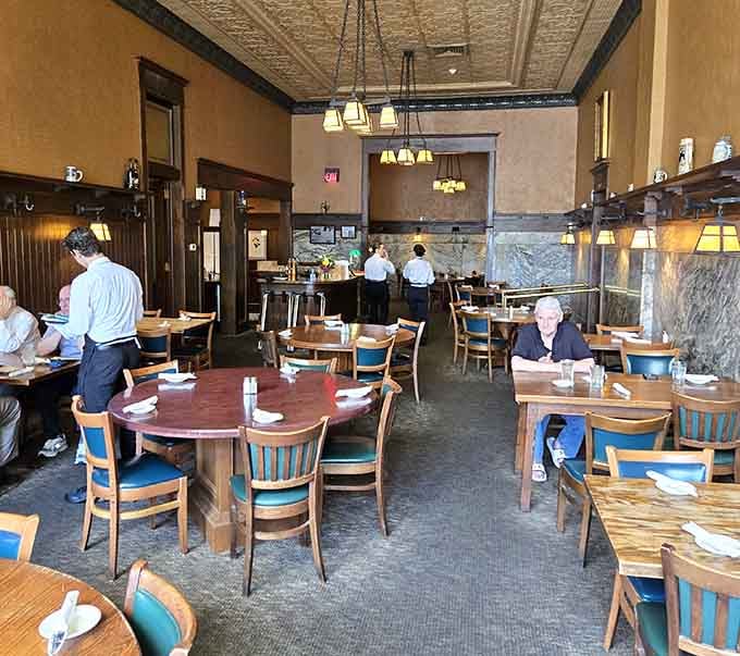 Dark wood, pressed tin ceilings, and blue-cushioned chairs. This dining room means serious, unhurried business.