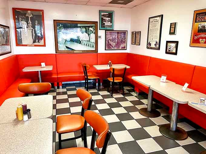 Black and white floors, orange chairs, and walls full of stories. This dining room earns its keep twice over.