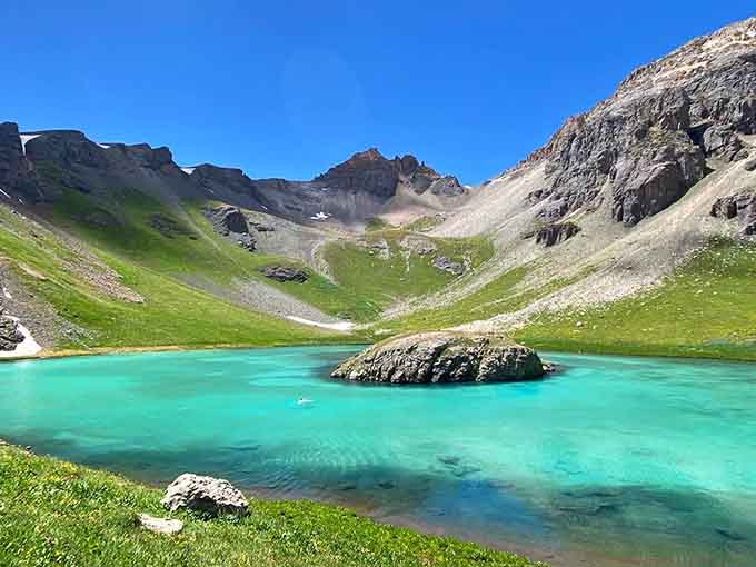 A lone boulder sits in turquoise water so clear and vivid, your eyes genuinely question what they're seeing.