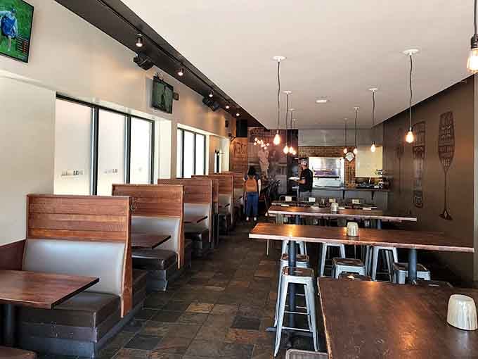 Wooden booths, warm pendant lights, and metal stools create a space that says "stay a while" without asking twice.