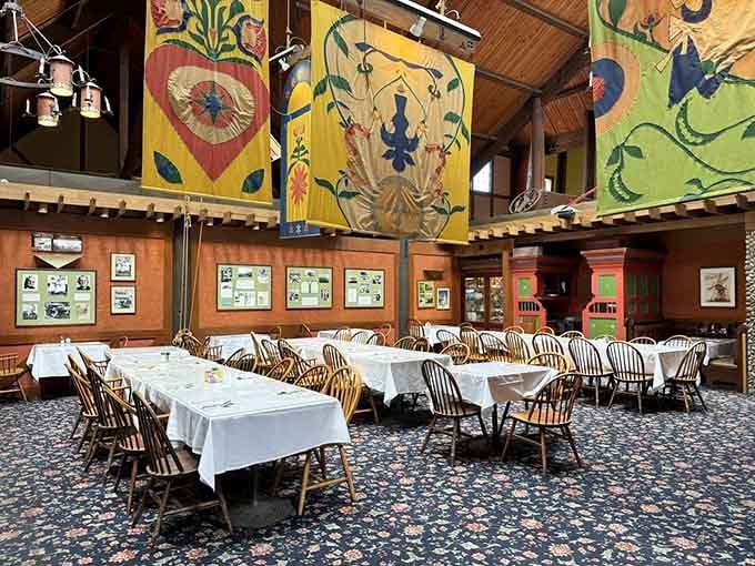 Bold folk art banners, white tablecloths, and Windsor chairs make this dining room feel like a warm Scandinavian hug.